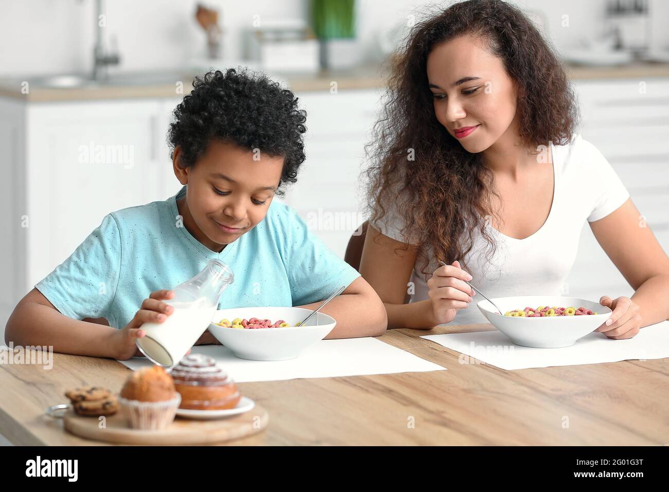 Little boy with mother eating cornflakes at home Stock Photo - Alamy