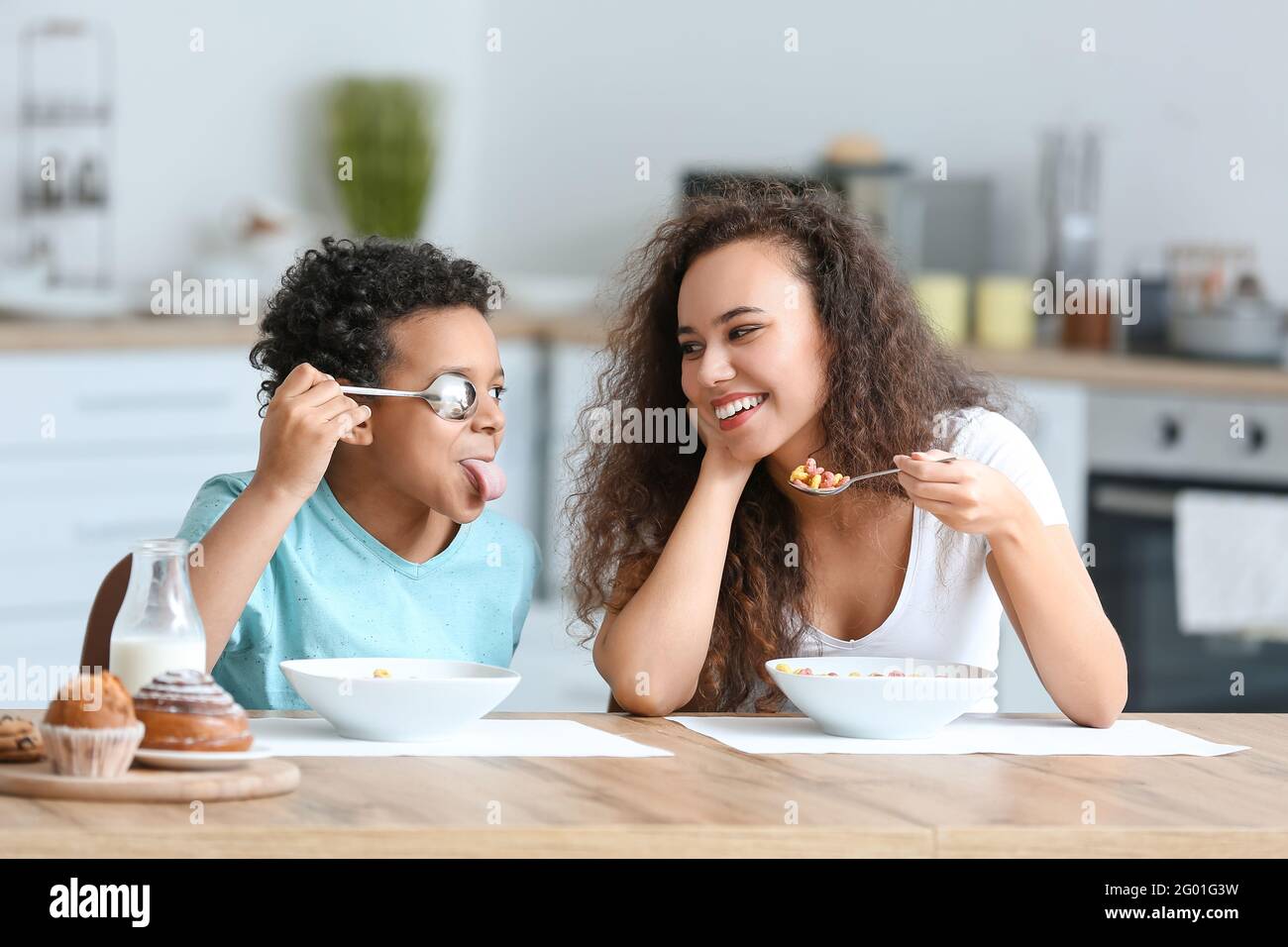 Little boy with mother eating cornflakes at home Stock Photo - Alamy