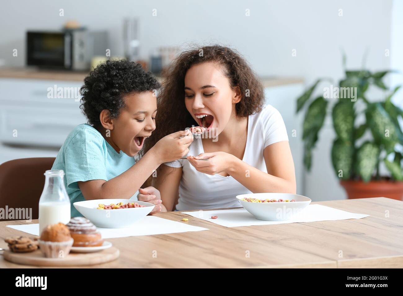 Little boy with mother eating cornflakes at home Stock Photo - Alamy
