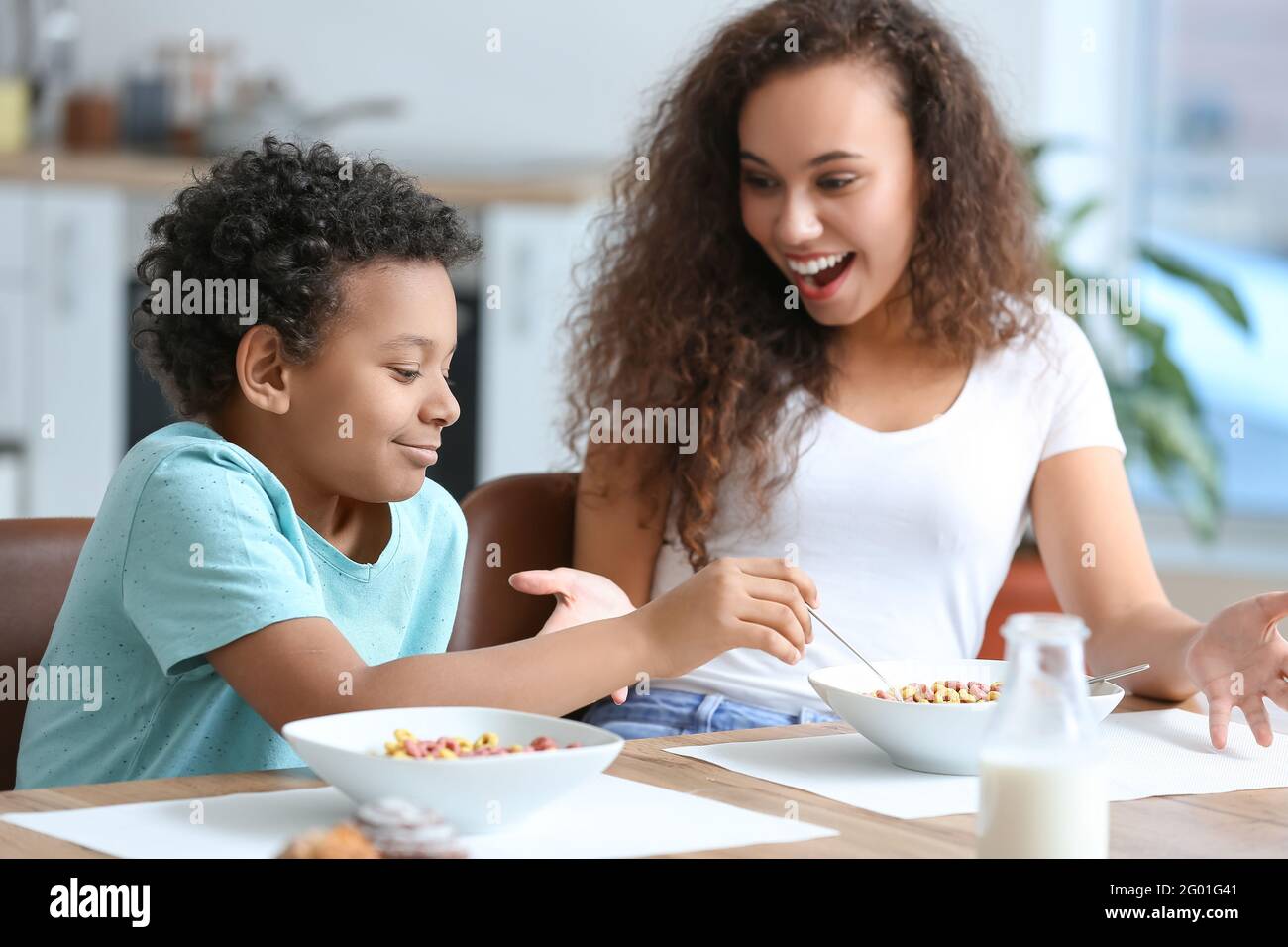Little boy with mother eating cornflakes at home Stock Photo - Alamy