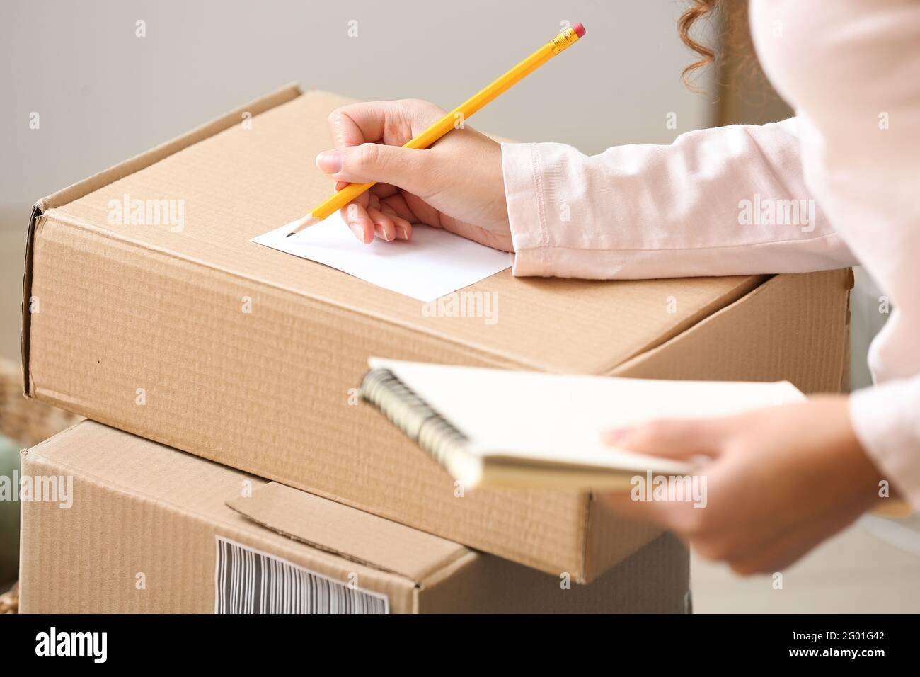 Young woman with parcel writing on sheet of paper, closeup Stock Photo ...
