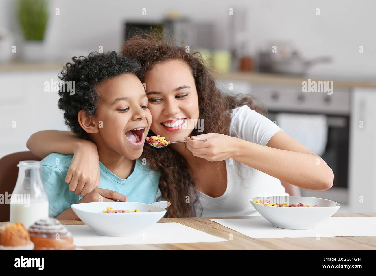 Little boy with mother eating cornflakes at home Stock Photo - Alamy