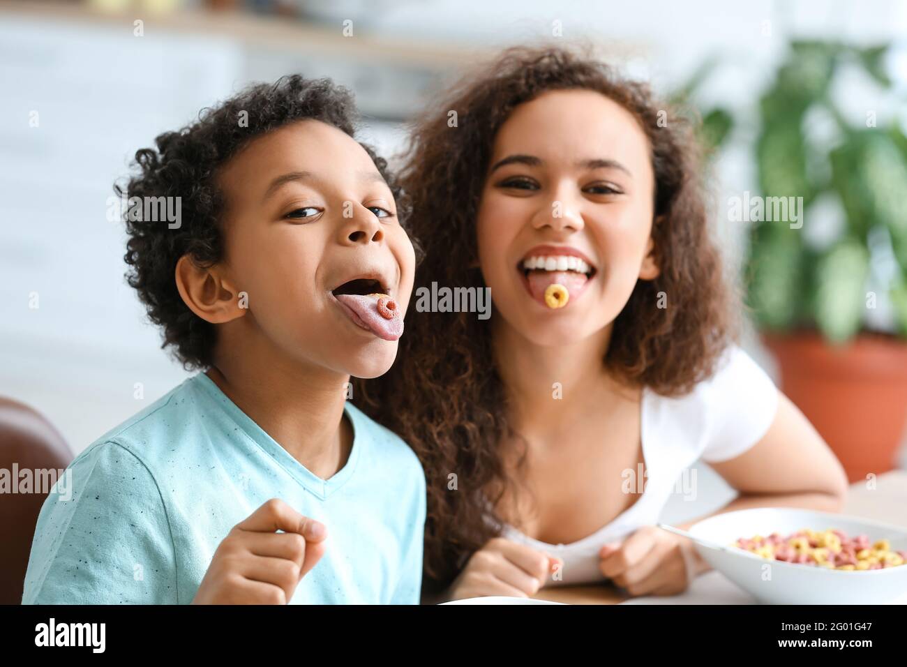 Little boy with mother eating cornflakes at home Stock Photo - Alamy