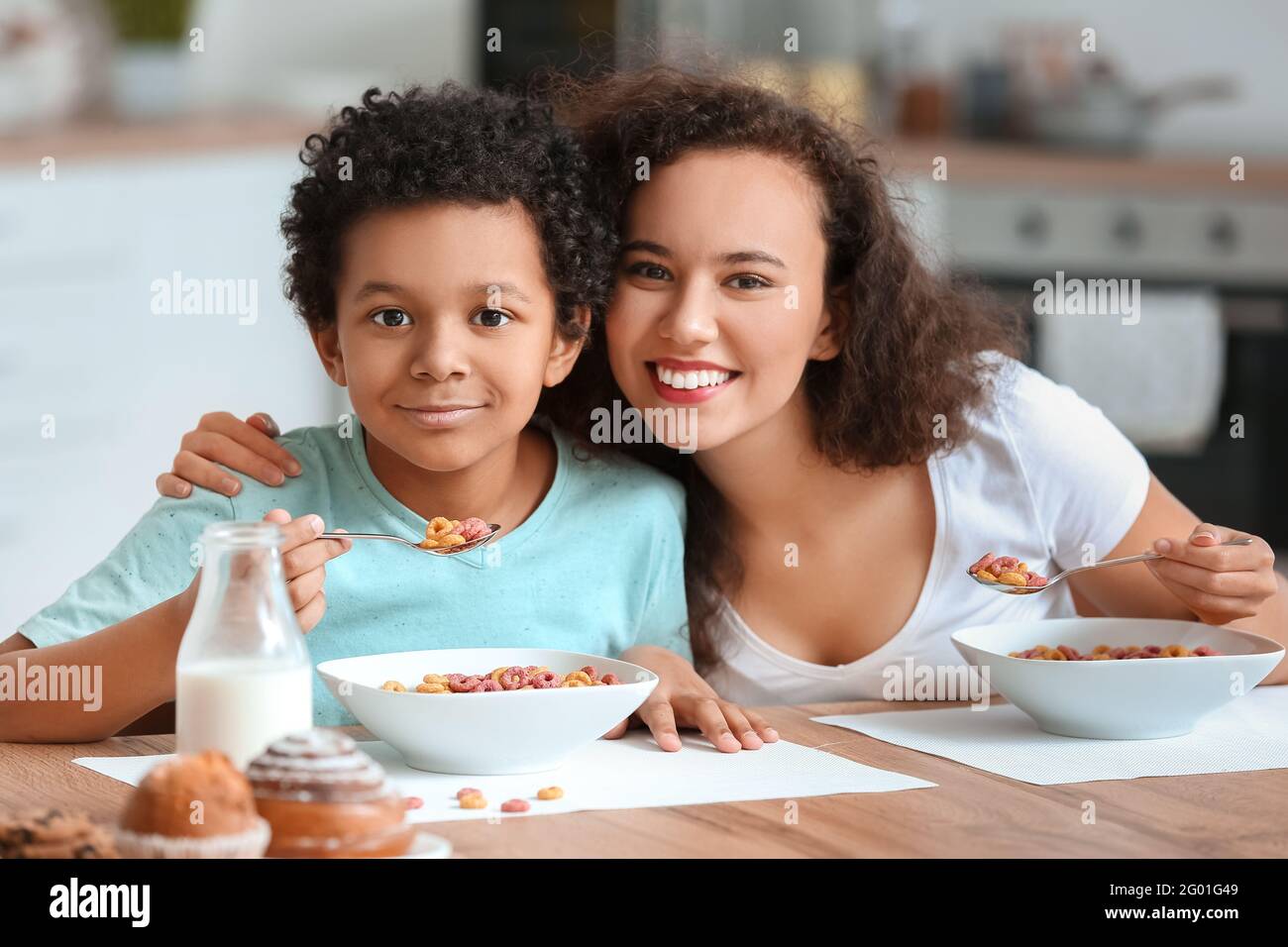 Little boy with mother eating cornflakes at home Stock Photo - Alamy