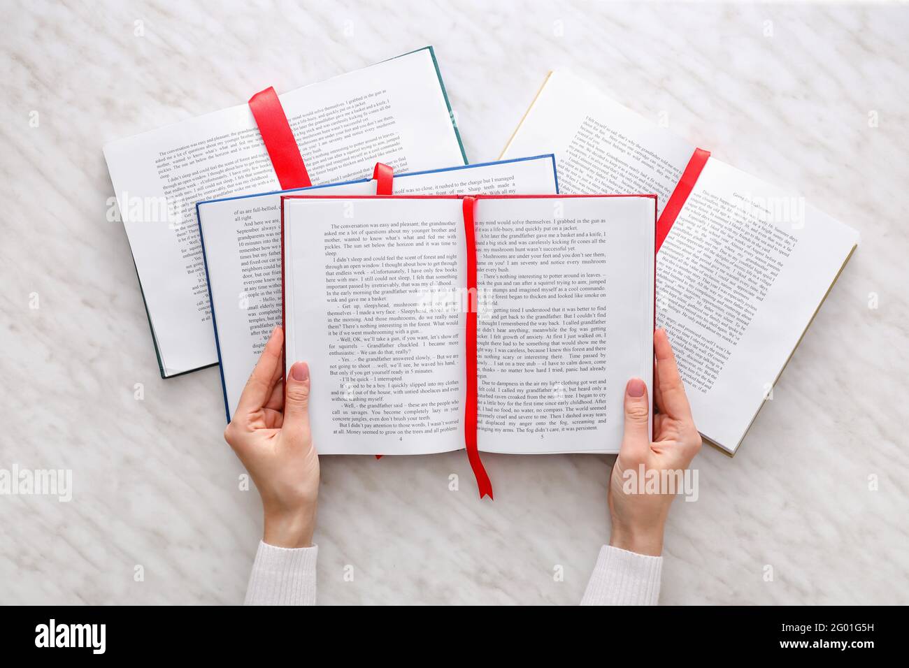 Woman holding open books with bookmarks on light background Stock Photo ...
