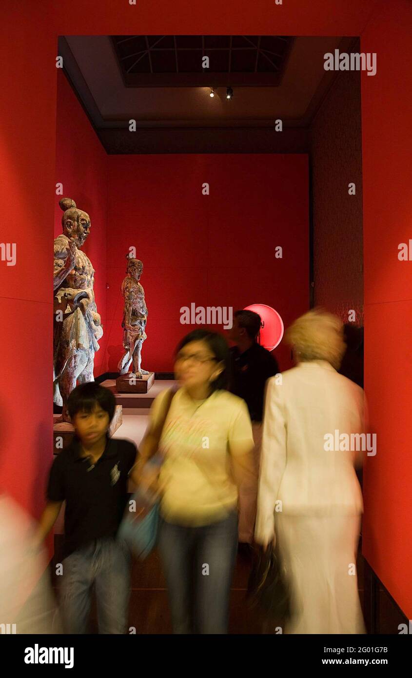 Visitors walking through a passage, in the background are two images of ...
