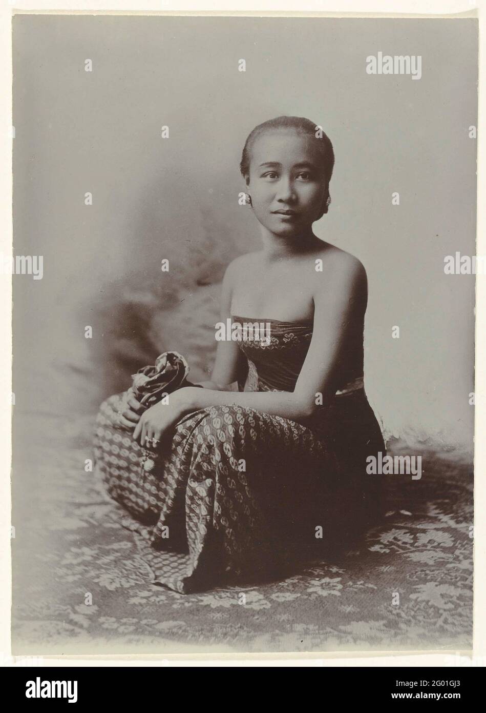 Studio portrait of a sitting young Javanese woman in a sarong with ...