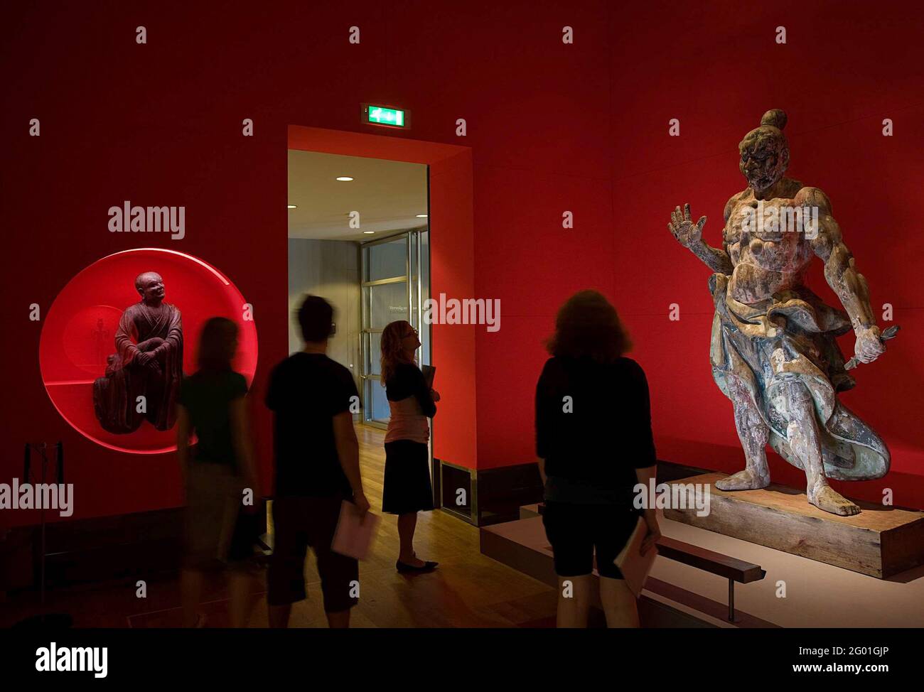 Visitors standing with an image of a Japanese temple guard, next to ...