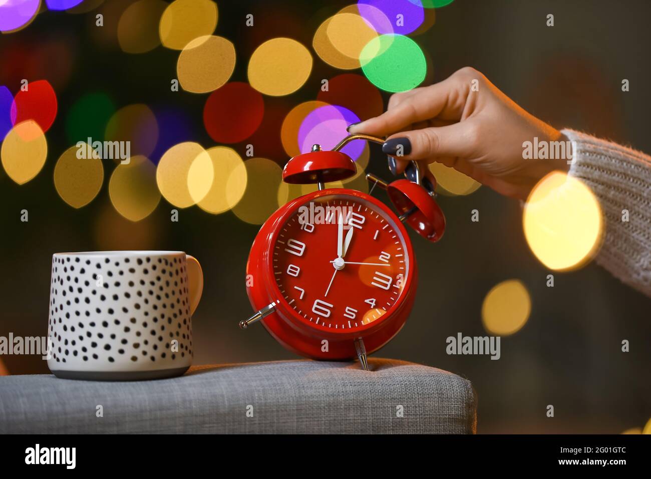Female hand and alarm clock on blurred background Stock Photo - Alamy