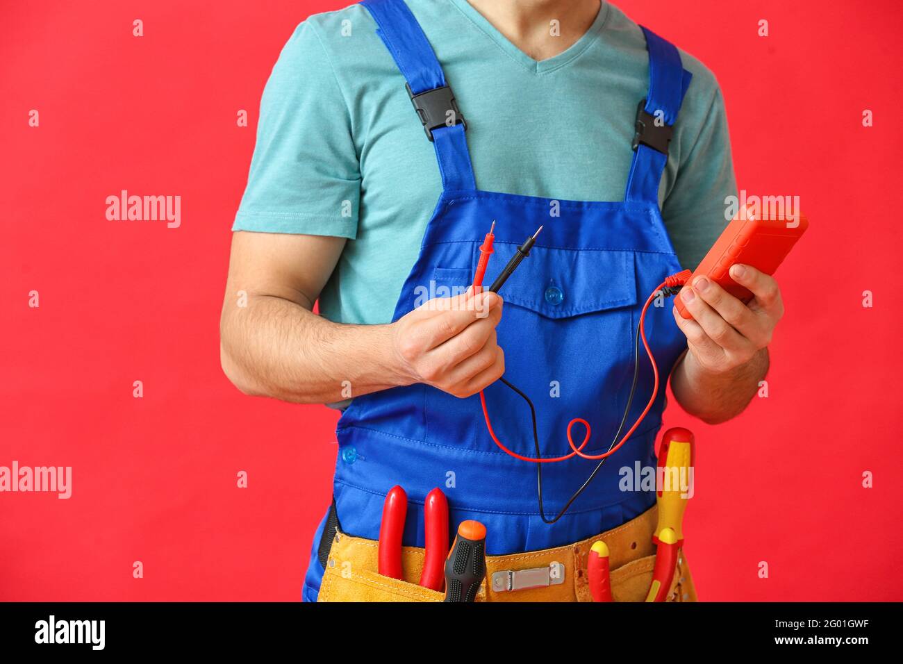 Young electrician with multimeter on color background Stock Photo - Alamy