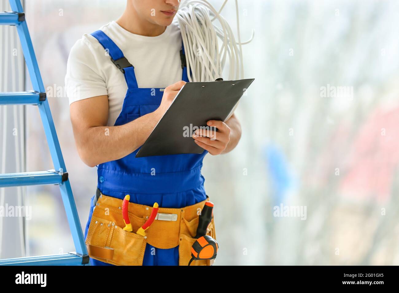 Young electrician writing in clipboard in room Stock Photo - Alamy