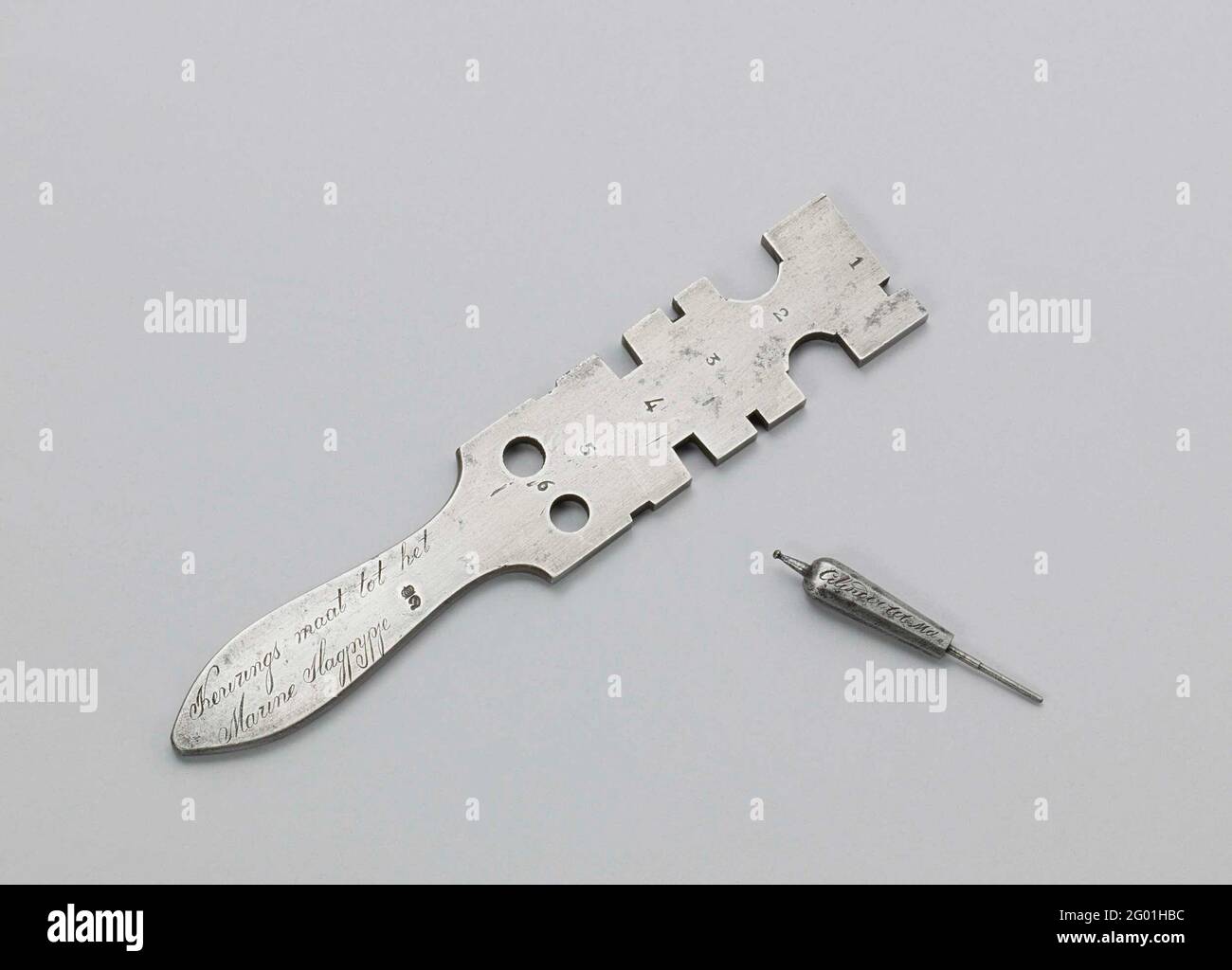 Gauge for priming tubes. A flat rectangular piece of iron with seven ...