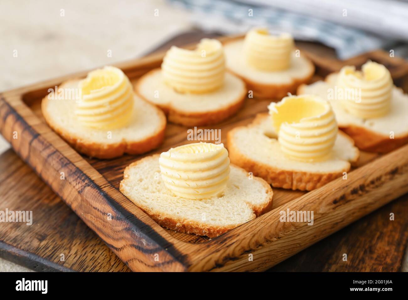 Wooden board with slices of fresh bread and butter on table,closeup ...