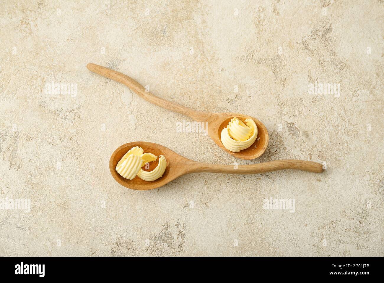 Wooden spoons with curls of butter on light background Stock Photo - Alamy
