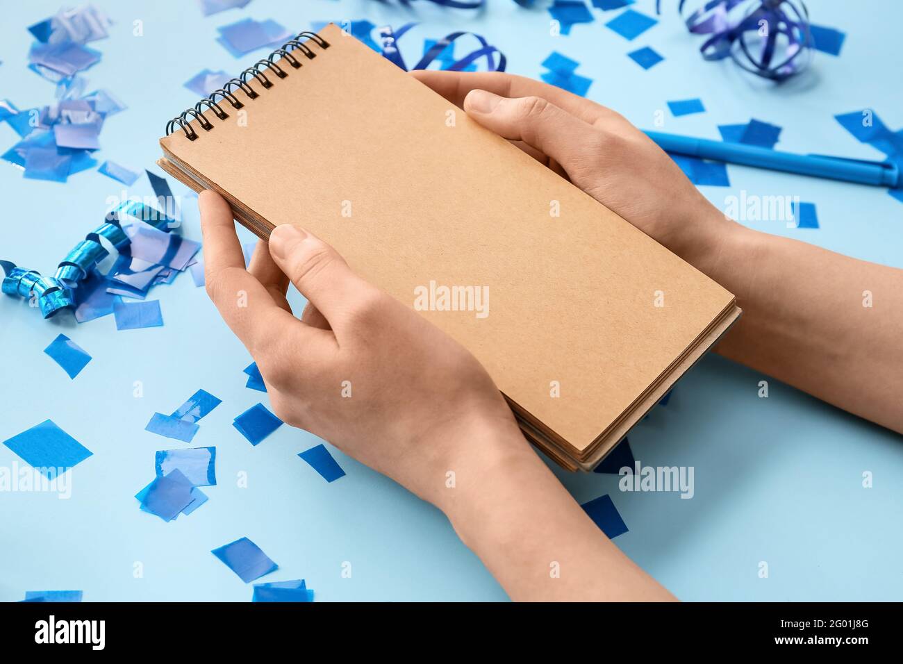 Female hands with blank notebook and confetti on color background Stock ...