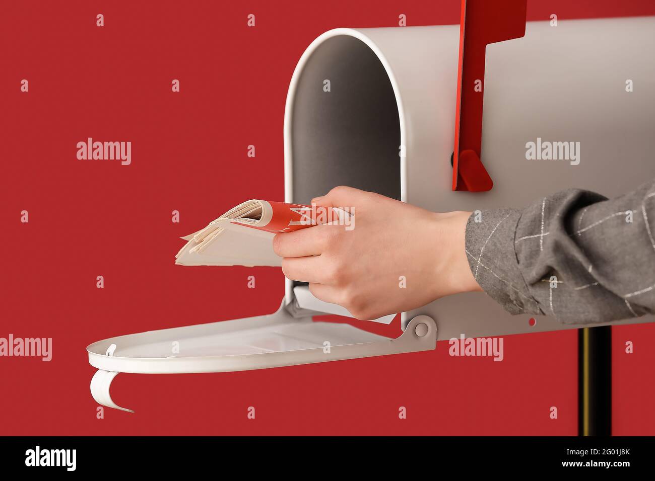 Woman getting newspaper from box on color background Stock Photo - Alamy