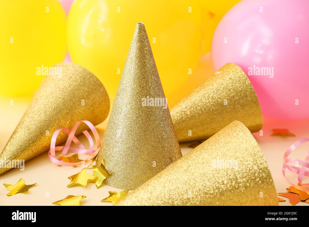 Party cones with confetti and air balloons on color background Stock ...