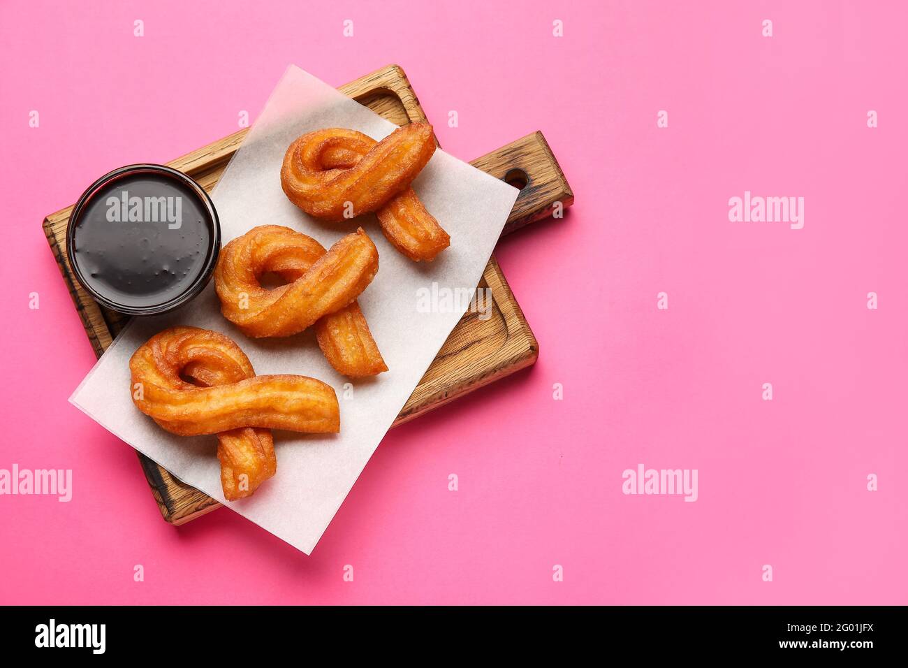 Board with tasty churros and melted chocolate sauce on color background ...