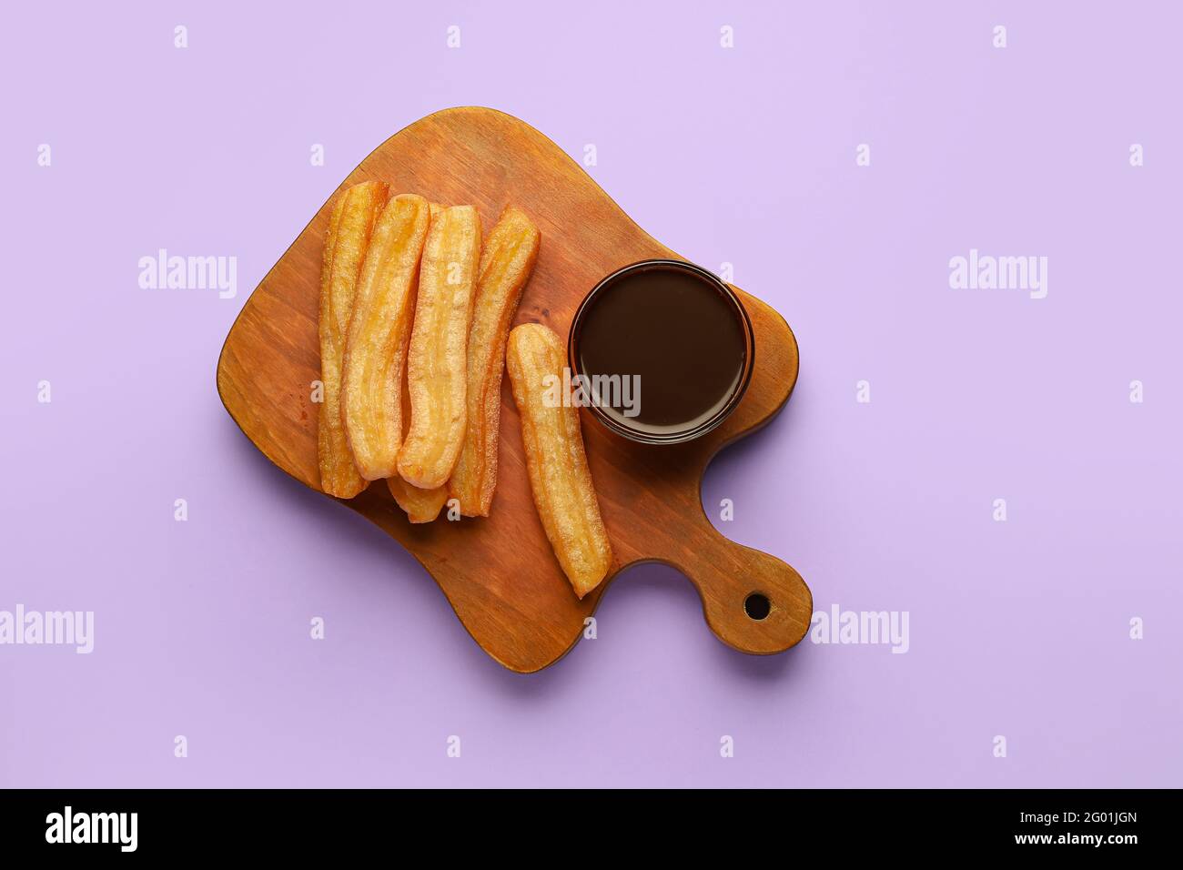 Board with tasty churros and melted chocolate sauce on color background ...