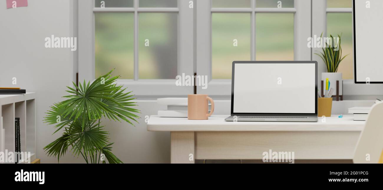 Laptop with mock-up screen on computer table beside the window in home ...
