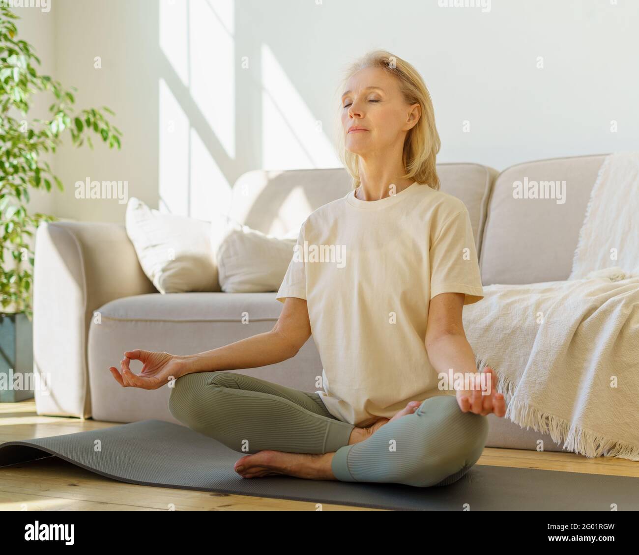 Peaceful senior woman in lotus position meditation with closed eyes at ...