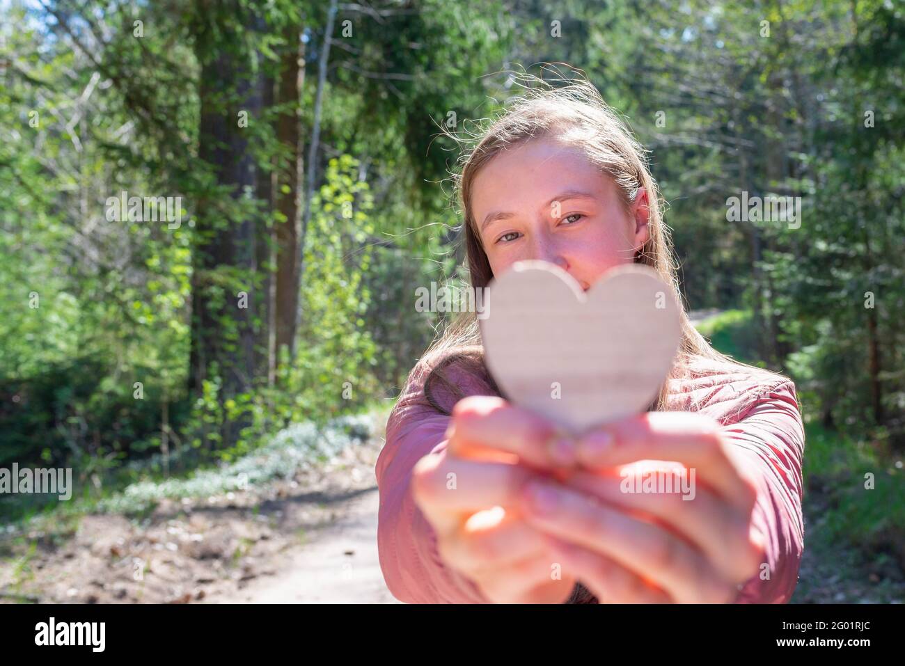 One joyful teen girl in forest holding a wooden heart in her hands.On ...