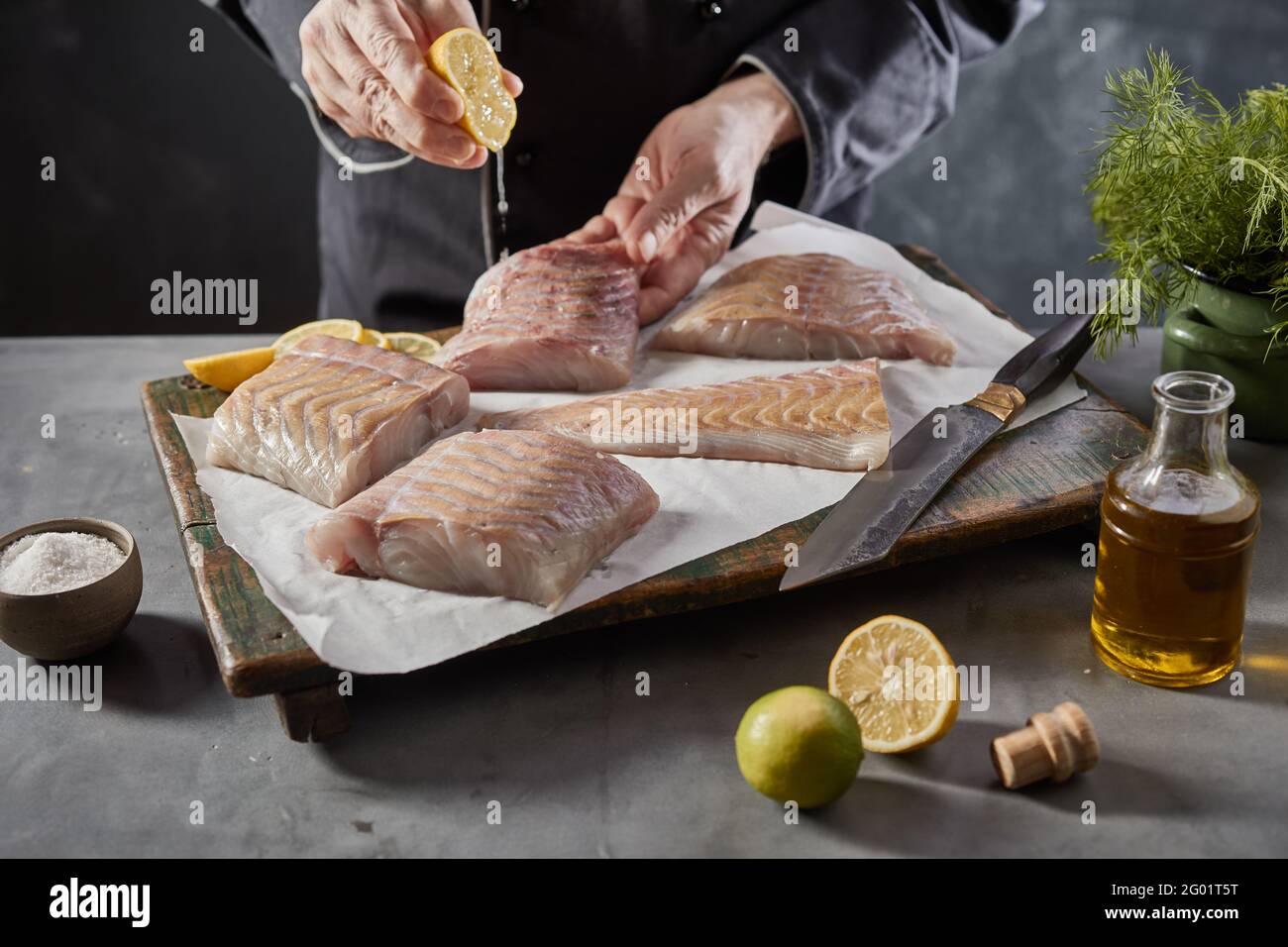 Crop unrecognizable cook seasoning raw fish fillet with lemon juice ...