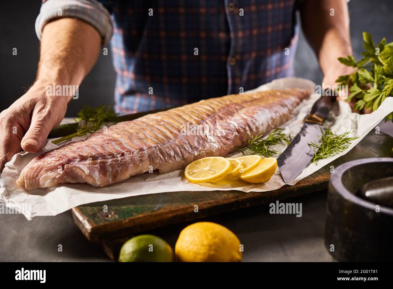 Crop unrecognizable male preparing pollock fish fillet with aromatic ...