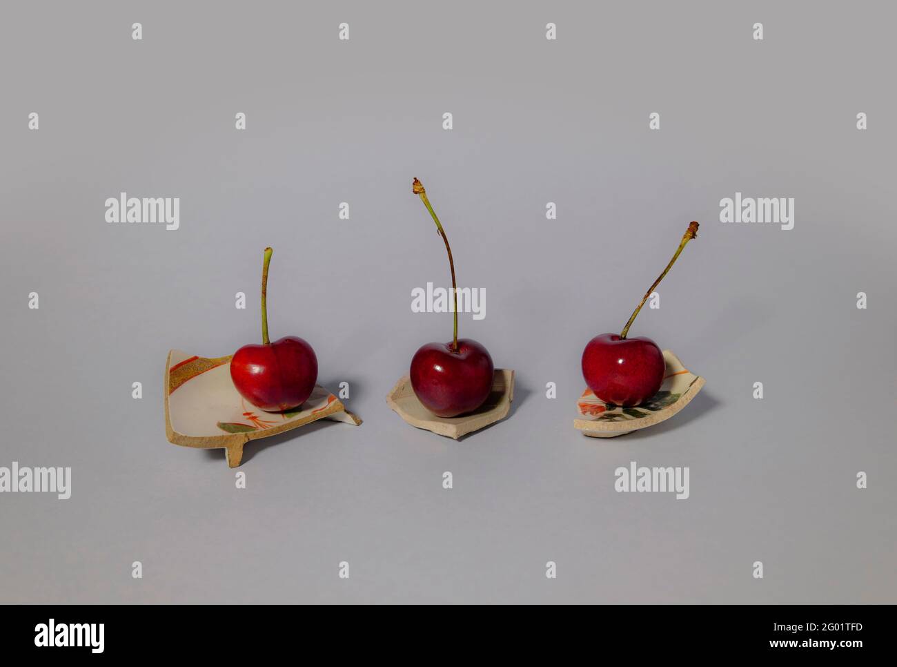 Cherries on broken chinese antique ceramic, with a grey background ...