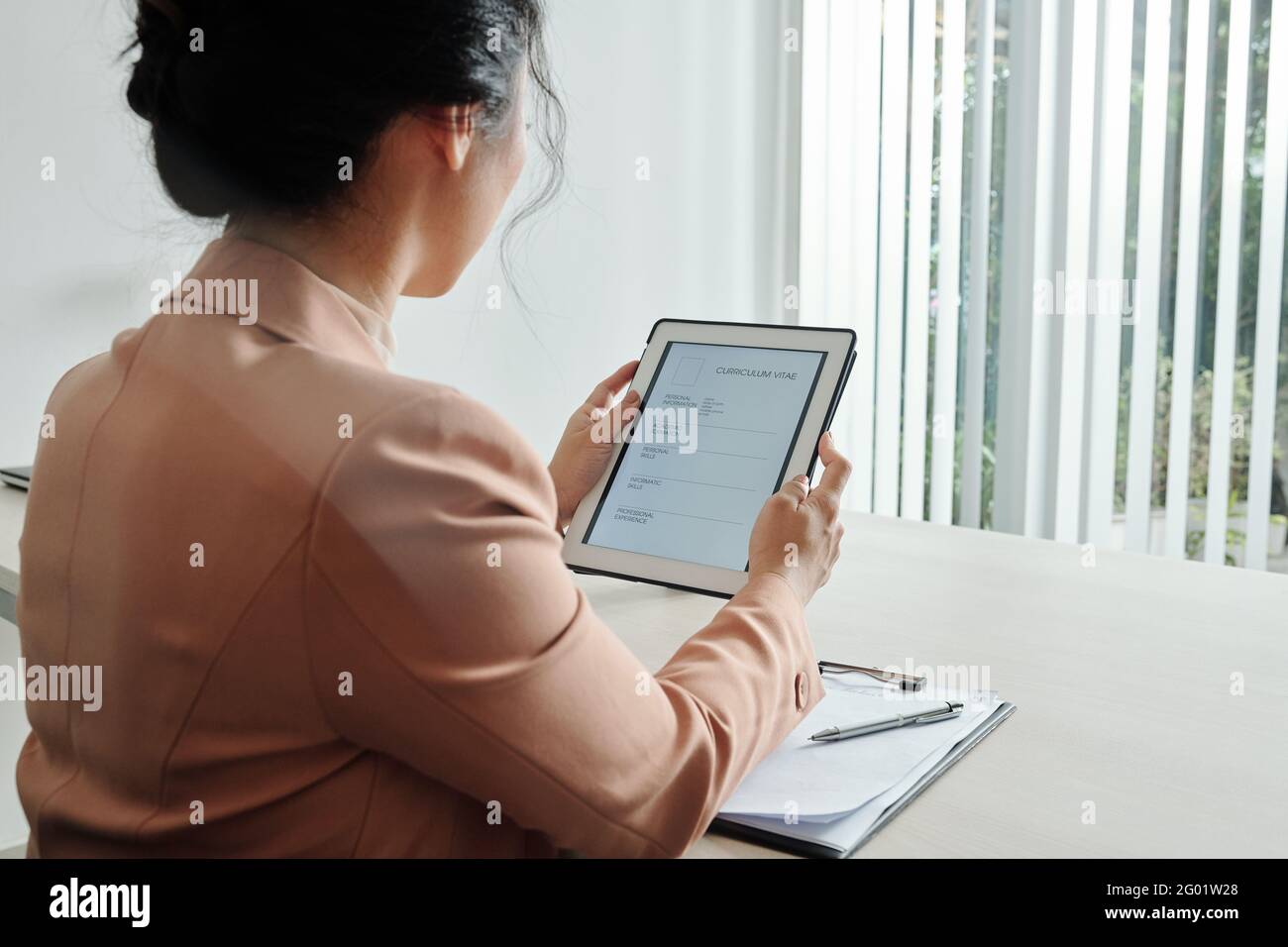 Young woman filling cv form on tablet computer, view from the back ...