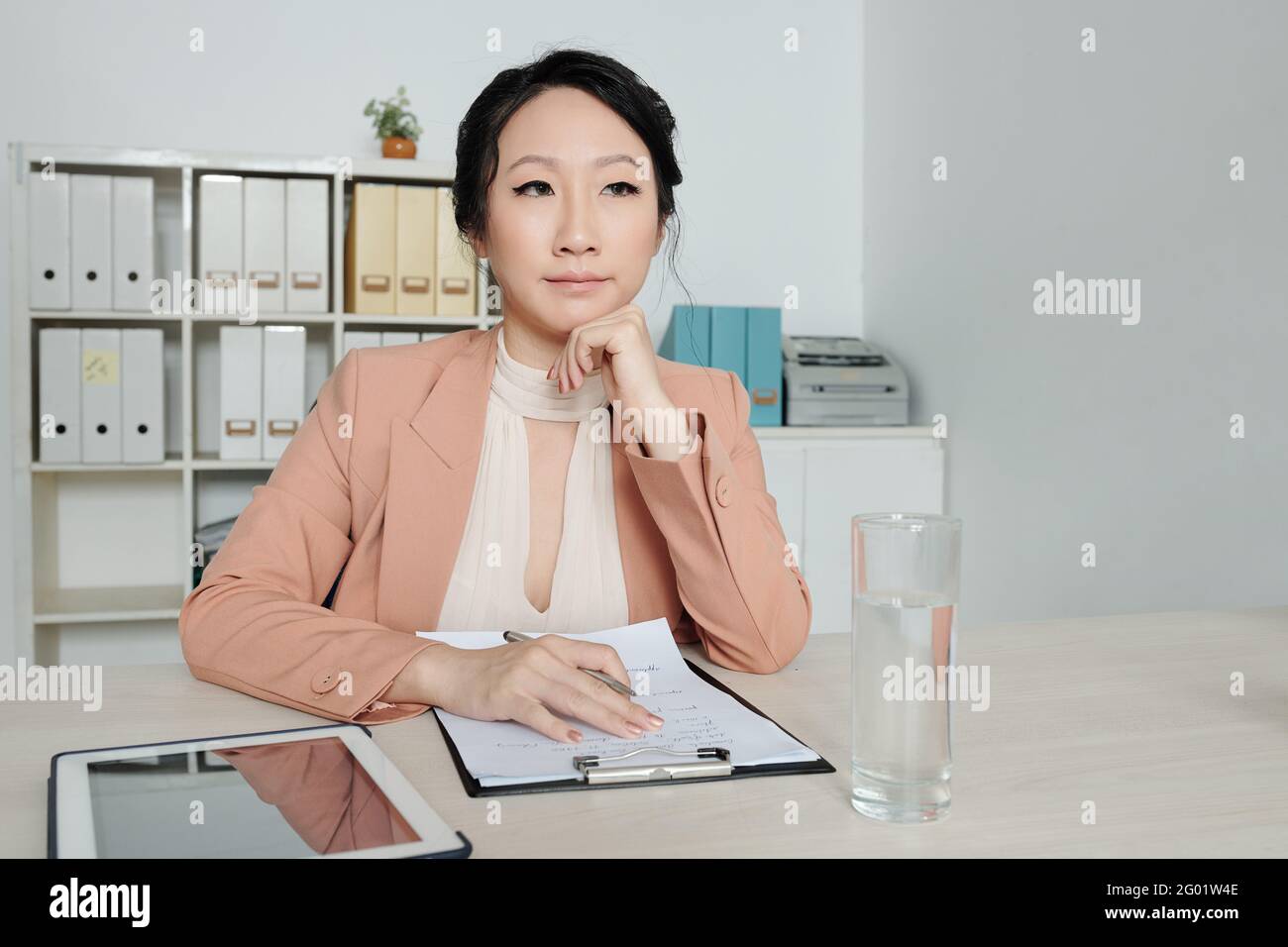 Pensive female human resource manager writing list of job requirements ...