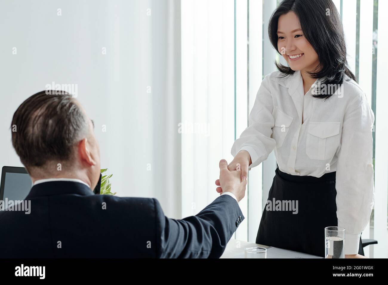 Pretty young businesswoman shaking hands of head of department before ...