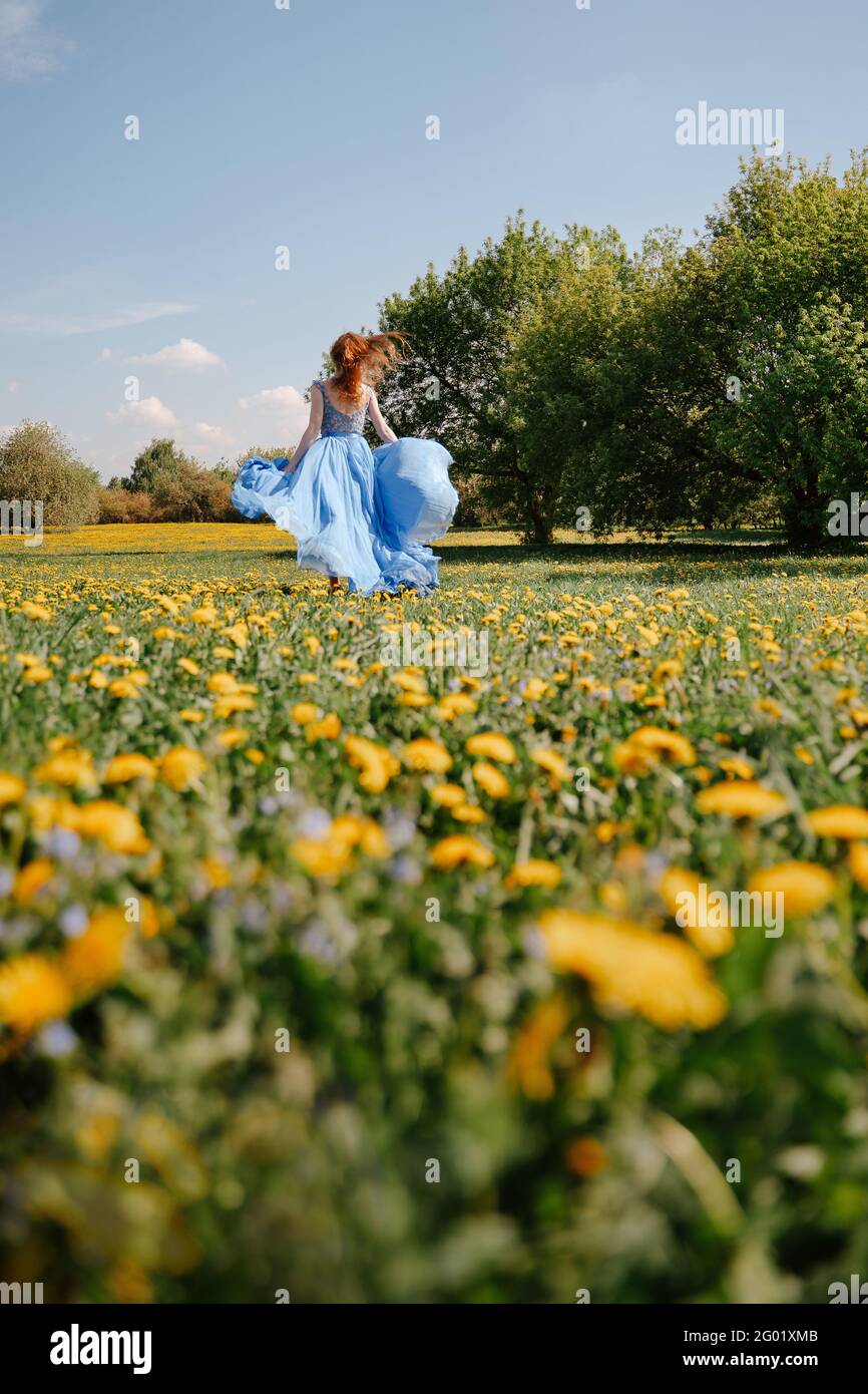 A fairy-tale girl runs across a field with meadow flowers Stock Photo ...