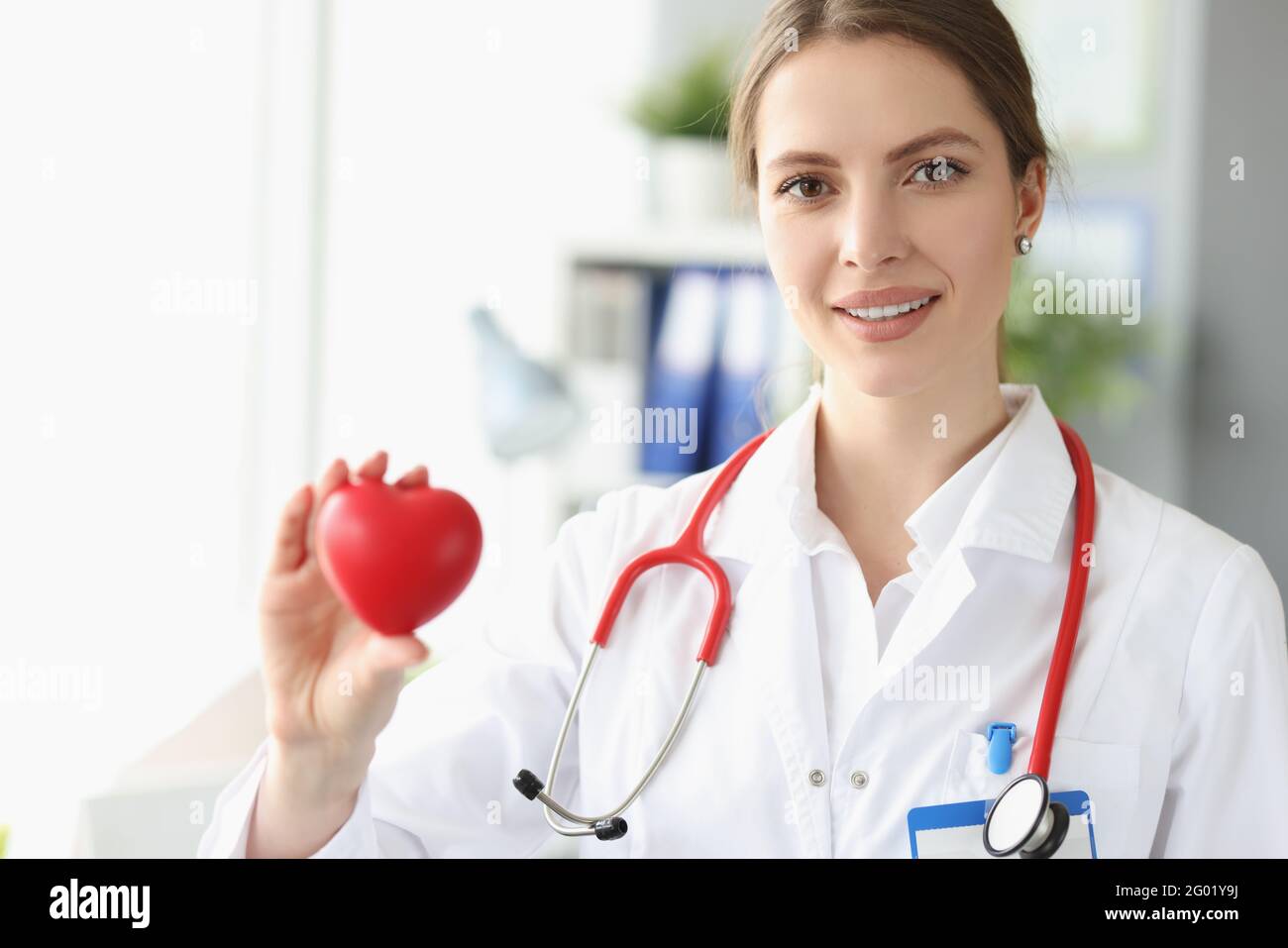 Portrait of female doctor cardiologist with small heart in her hand ...