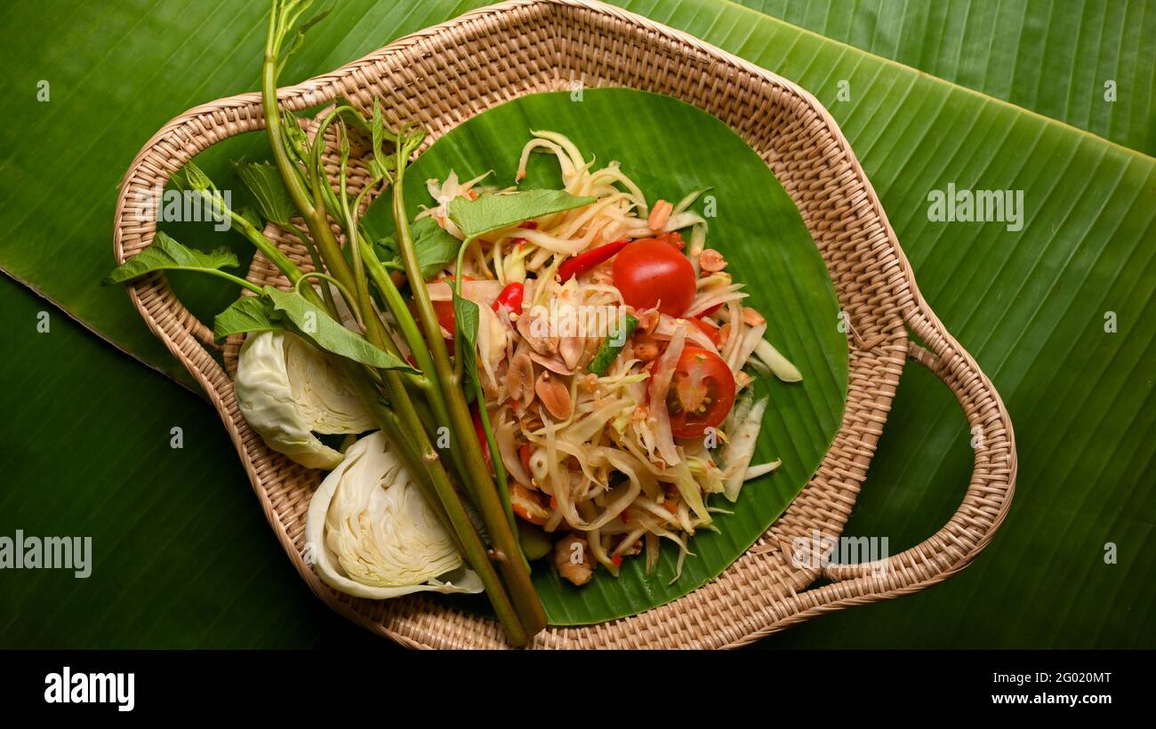 Thai food, papaya salad (Somtum) serving with vegetable on wicker tray ...