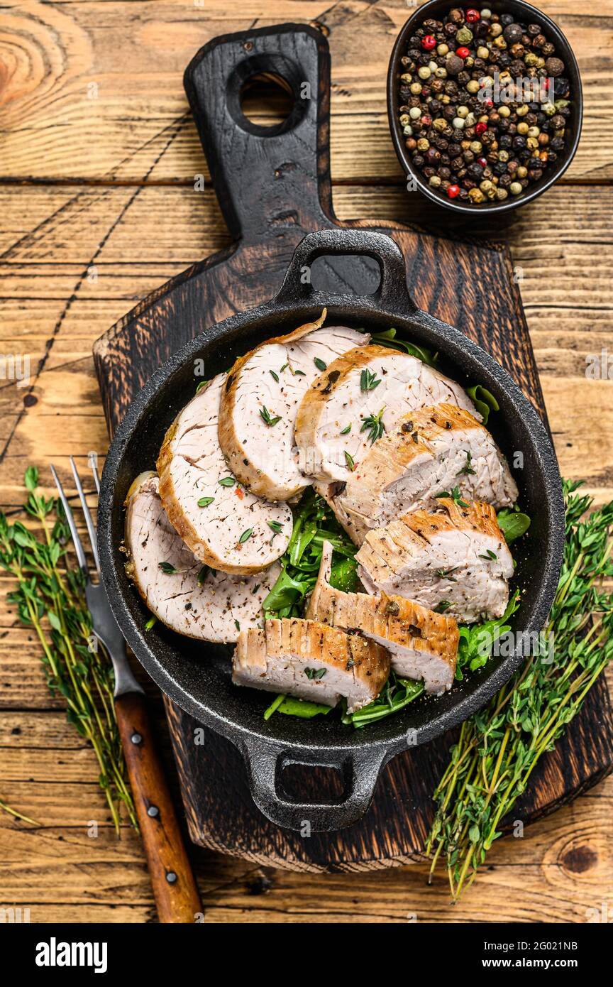 Sliced grilled pork tenderloin steak in a pan. Wooden background. Top ...
