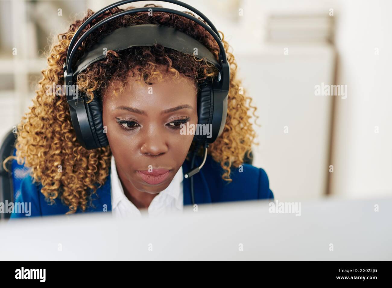 Portrait of serious female technical support operator in headphones ...