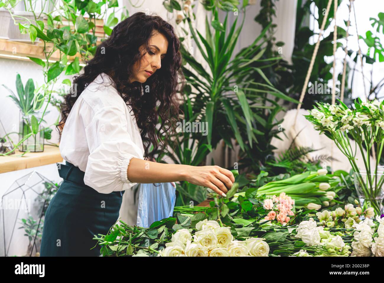 Attractive young woman florist is working in a flower shop Stock Photo ...