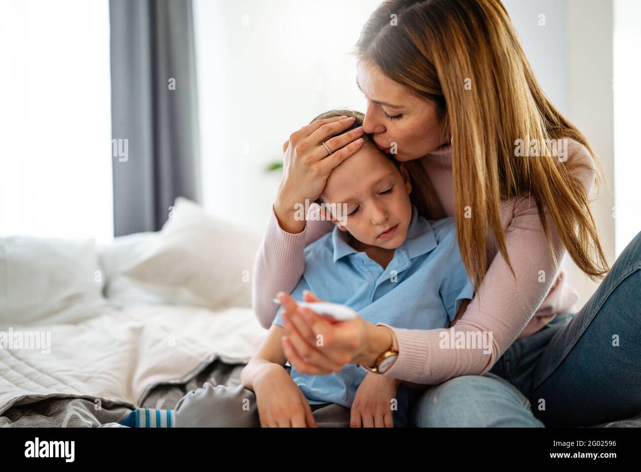 Mother measuring temperature of her ill kid. Sick child with high fever, mother holding ...