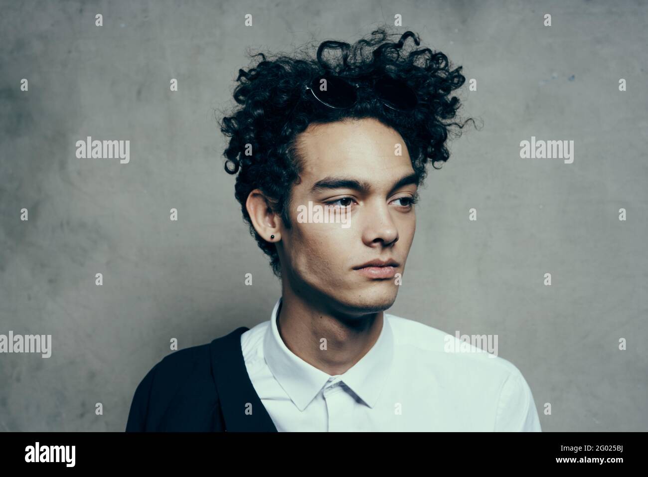 handsome guy with curly hair in a white shirt and jacket on a gray ...