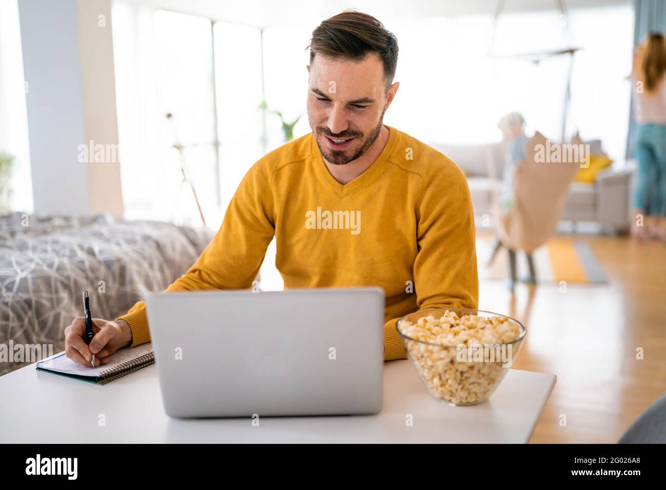 Work from home. Man works on laptop with family playing around Stock ...