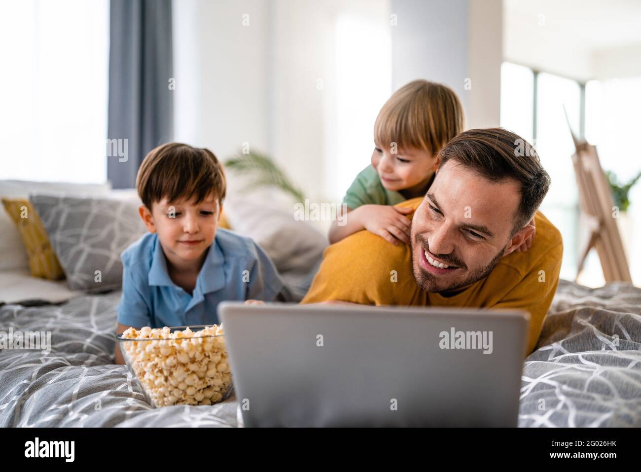 Overjoyed little children resting on bed with smiling dad, enjoying ...