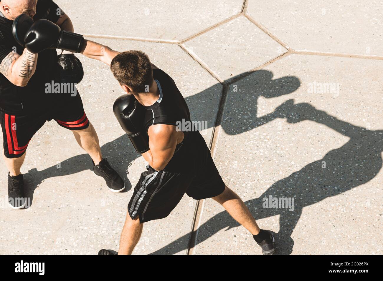 Two men exercising and fighting in outside. Boxer in gloves is training ...