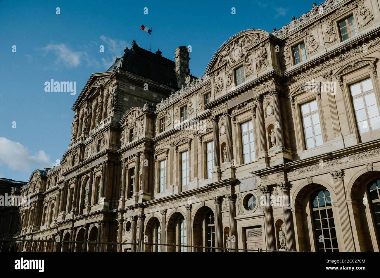 Low angle shot of the louvre museum building with french flag under the ...