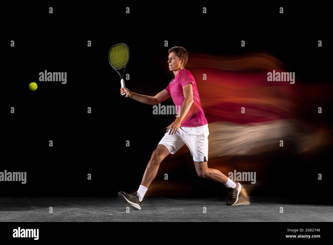 Young caucasian male tennis player playing tennis in mixed light on ...