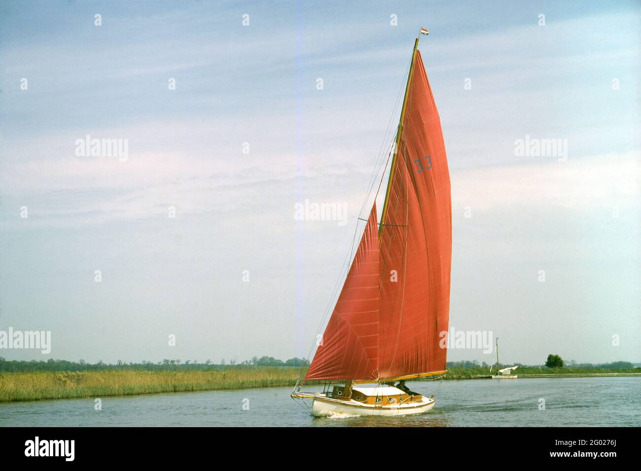 Bermuda-rigged sailing yacht with red sails on the river Bure, Norfolk ...