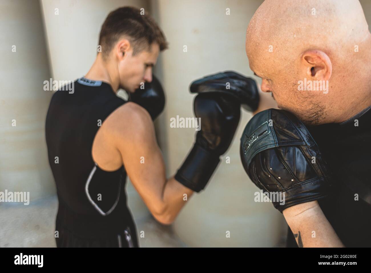 Two men exercising and fighting in outside. Boxer in gloves is training ...