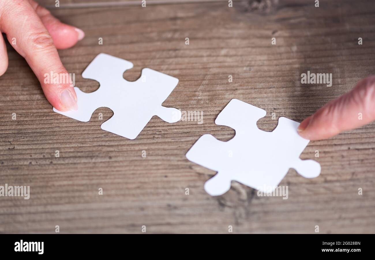 Hands joining two puzzle pieces, teamwork concept Stock Photo - Alamy