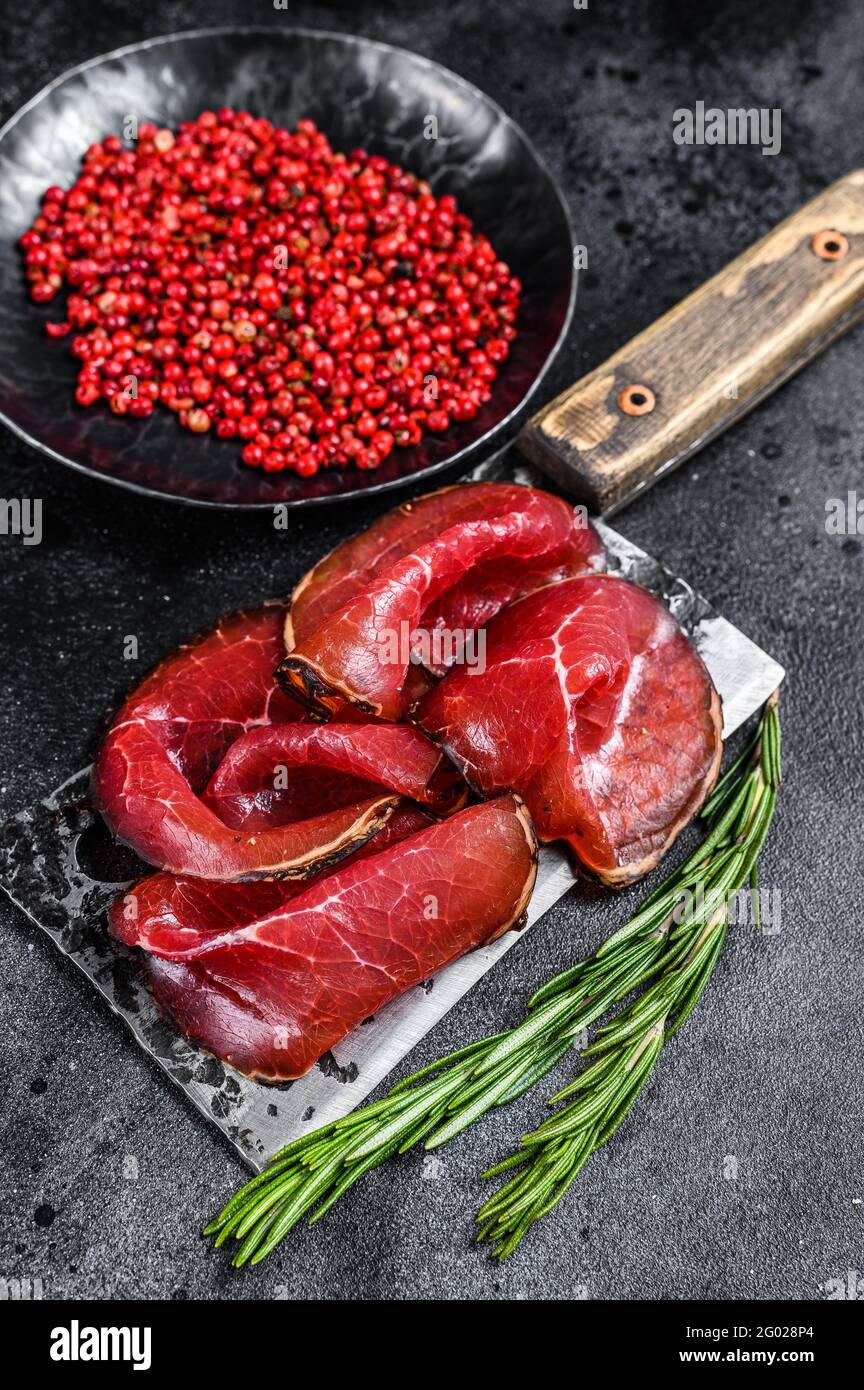 Bresaola dried beef meat sliced on a cleaver. Black background. Top ...