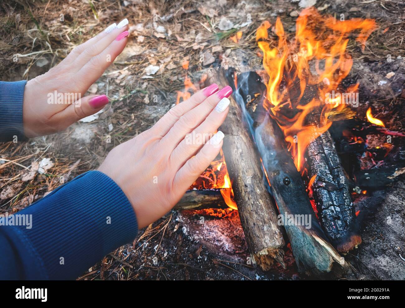 woman is making fire while camping outdoors, at the forest - warming up ...